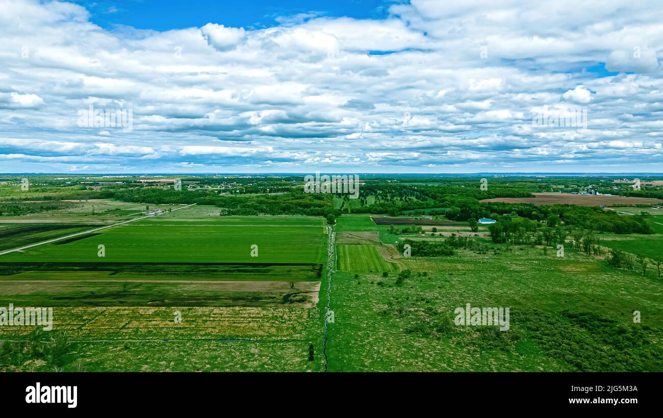 Green grass and trees far to the horizon. Clouds sweep over the ...