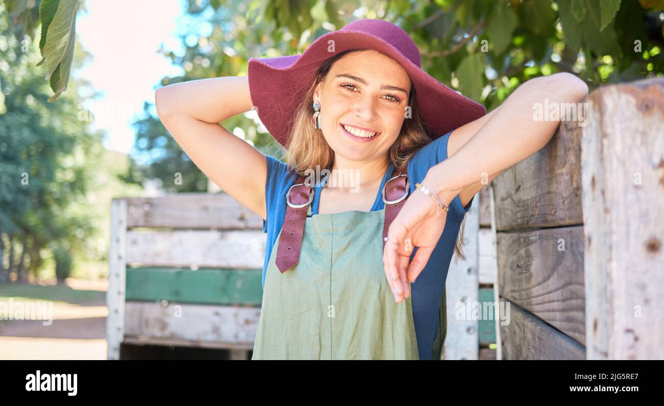 Portrait of a female farmer standing under a tree next to a rustic ...