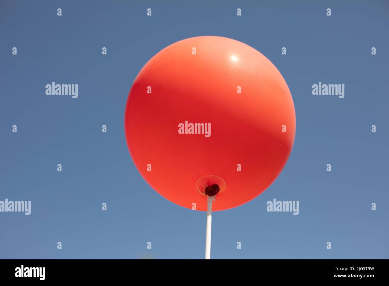 Red ball against sky. Round balloon of red color on stick. Details of ...