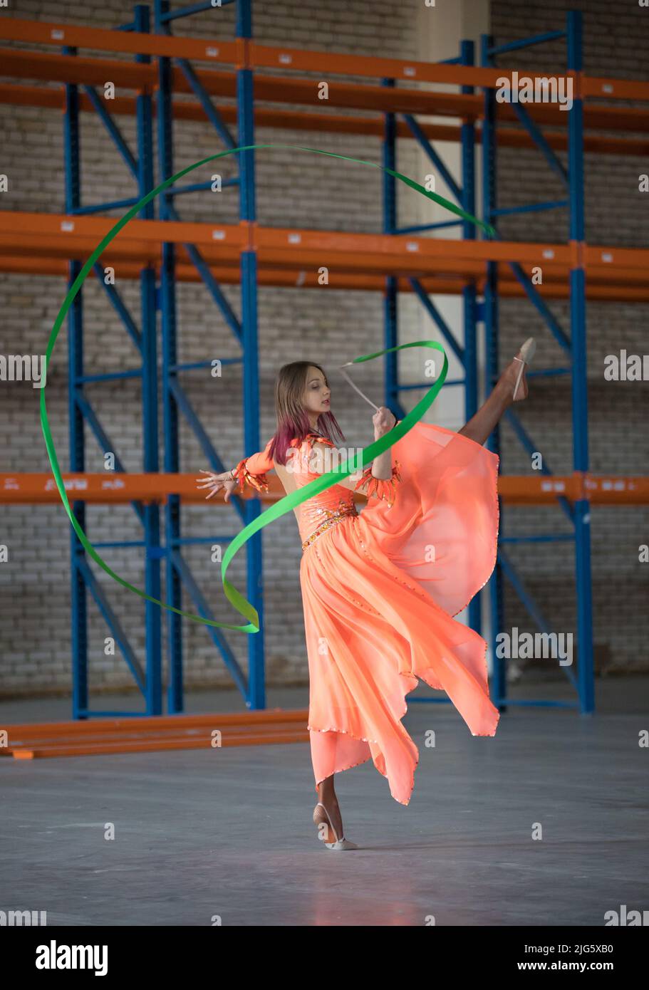 Young attractive woman dancing with gymnastic ribbon in hands indoor ...