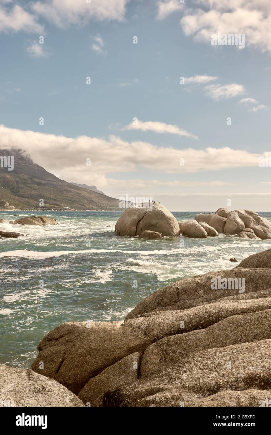 Rocks in the ocean under a blue cloudy sky with copy space. Scenic ...