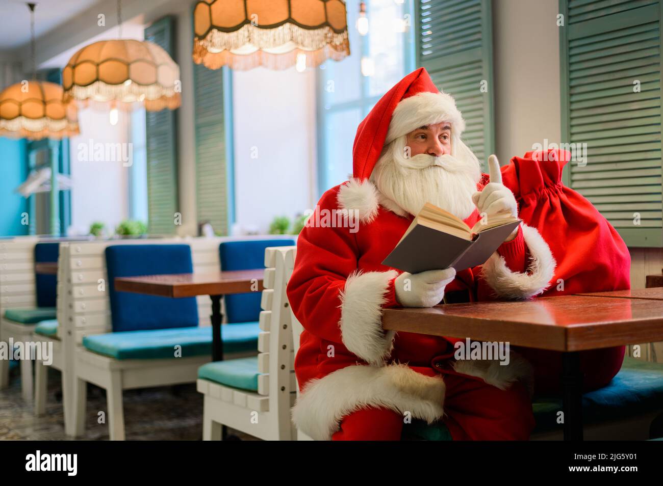 Santa Claus is sitting in a cafe and reading a book Stock Photo - Alamy
