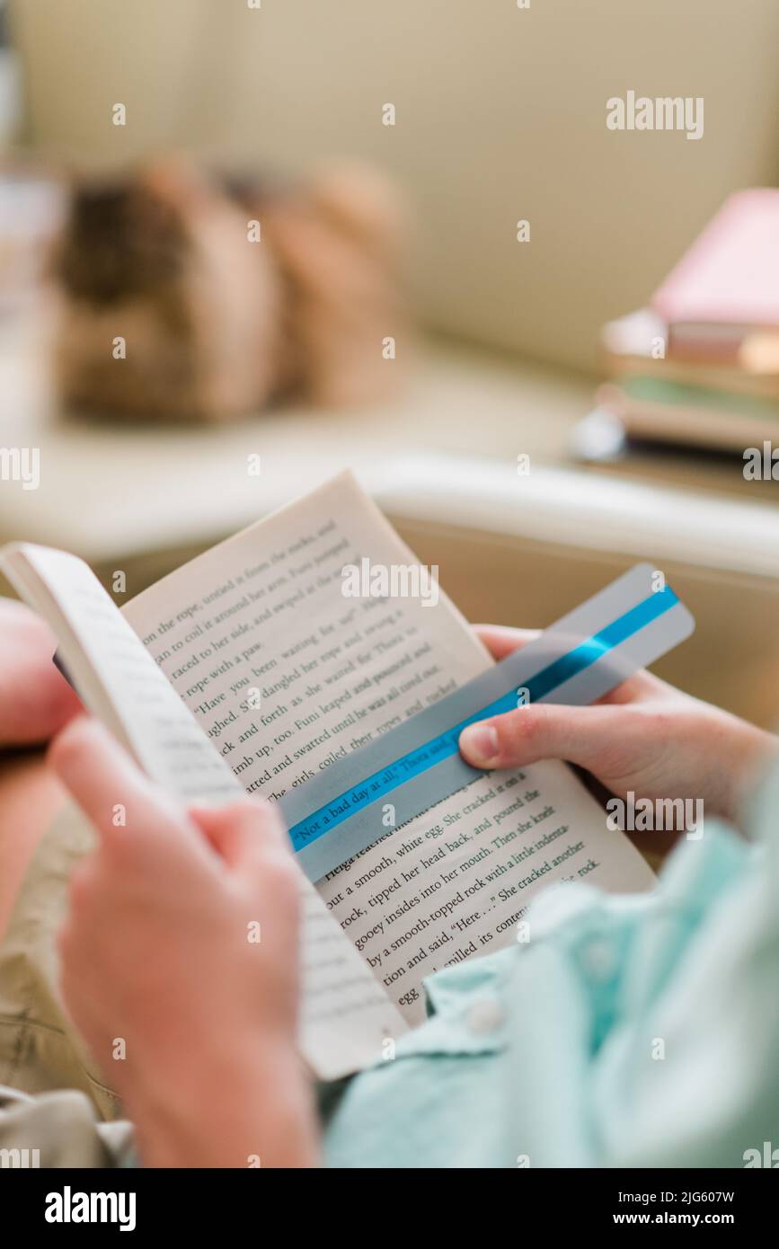 Dyslexic child reading with dyslexia color overlay in his book. A green ...