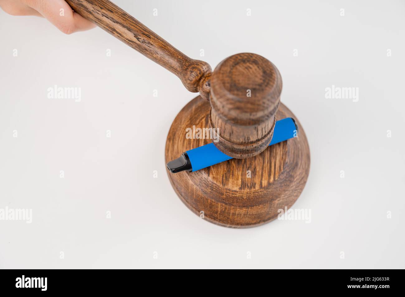 Judge hammering disposable vape with referee's gavel on white table ...