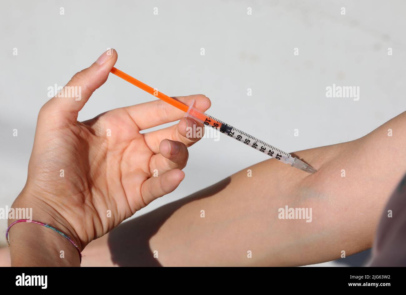 young girl with injected syringe on her arm while taking a dose Stock ...