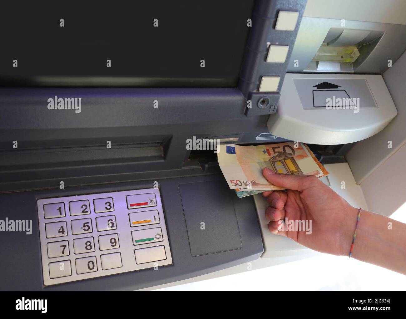 human hand taking euro banknotes from an ATM after typing the secret ...