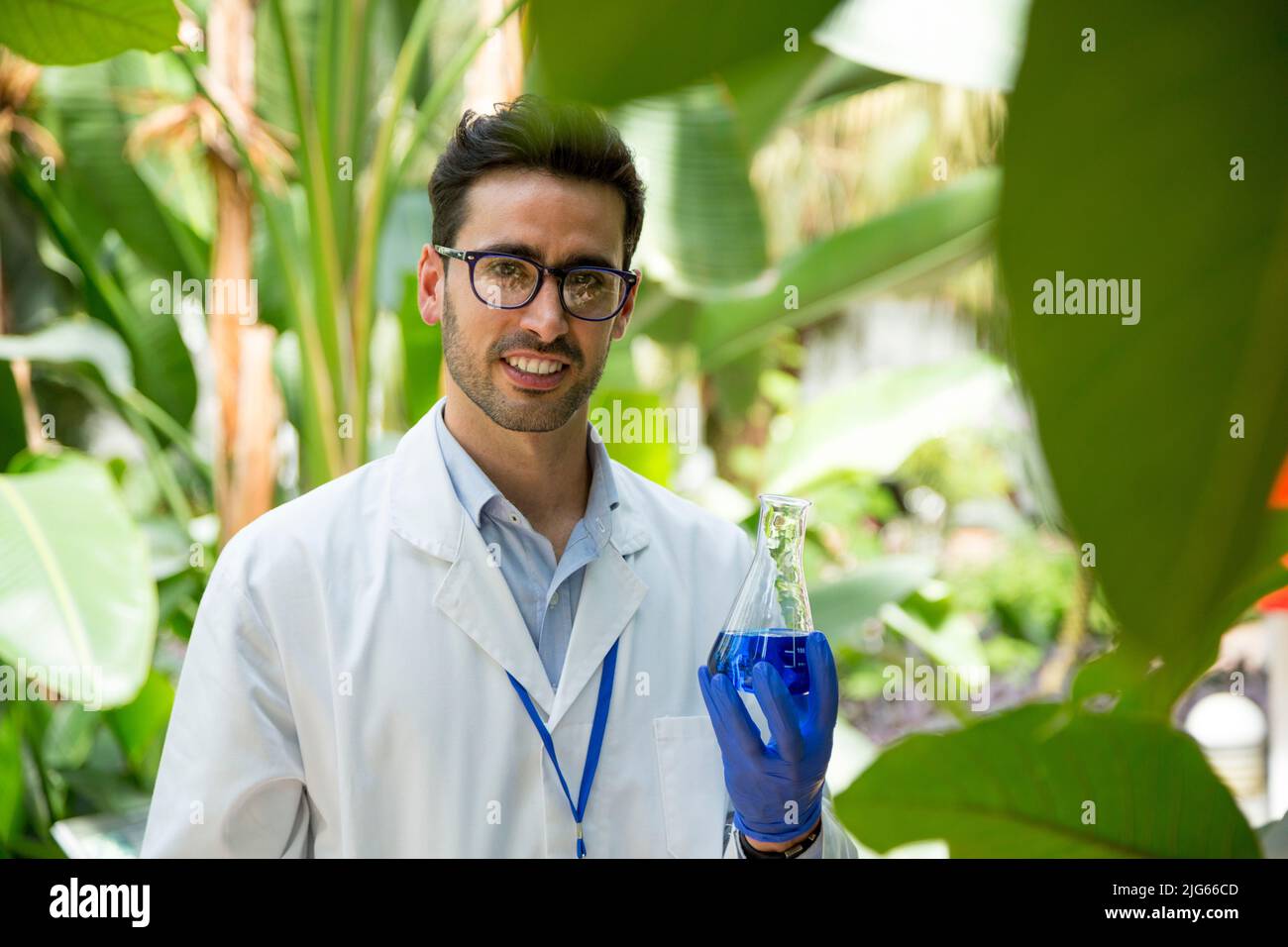 Smiley scientist in lab coat holding a lab flask with liquid in a ...