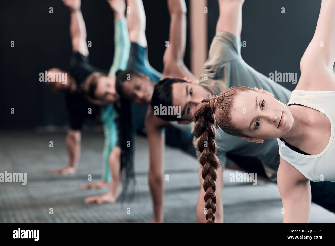 Feel that core burning. Shot of a group of gym friends side planking ...