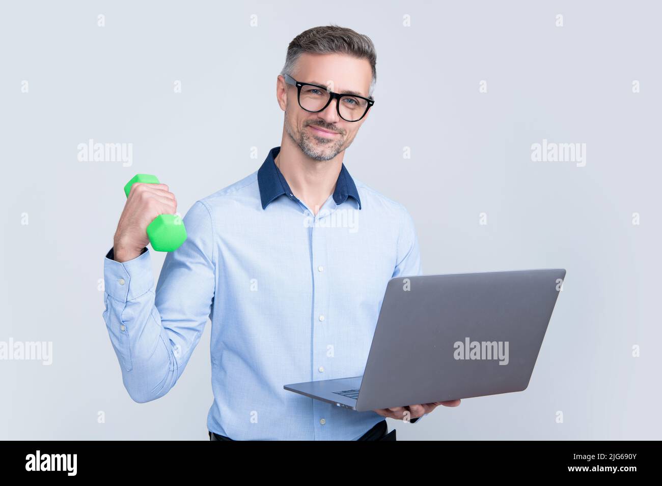 smiling mature man in eyeglasses working on computer with dumbbell on ...