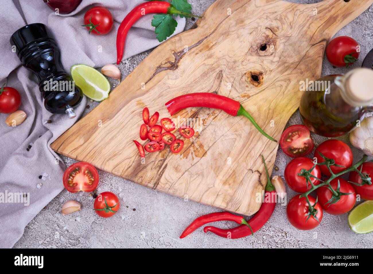 Fresh red chili peppers round slices on wooden cutting board at ...