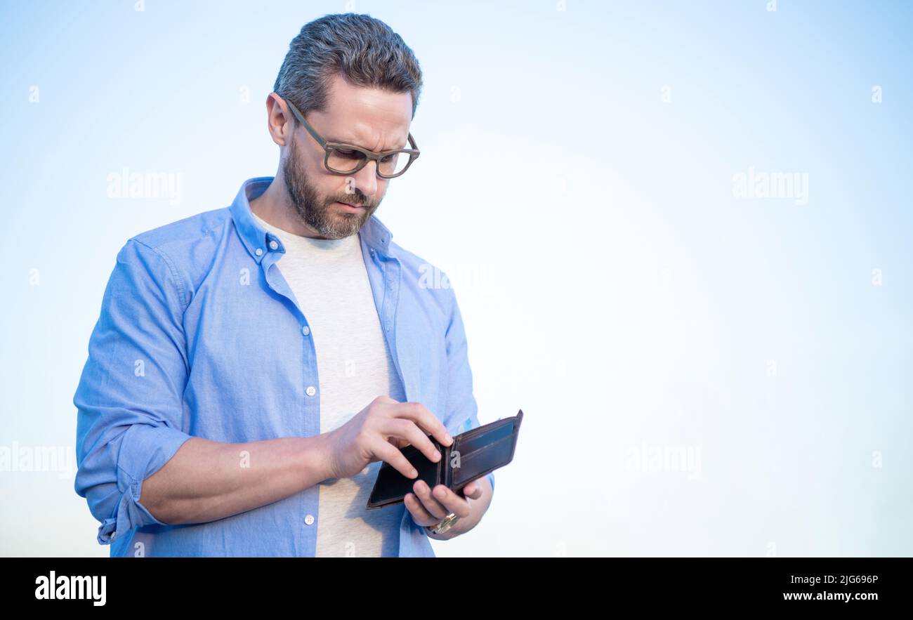Serious guy in glasses opening wallet sky background, copy space Stock ...