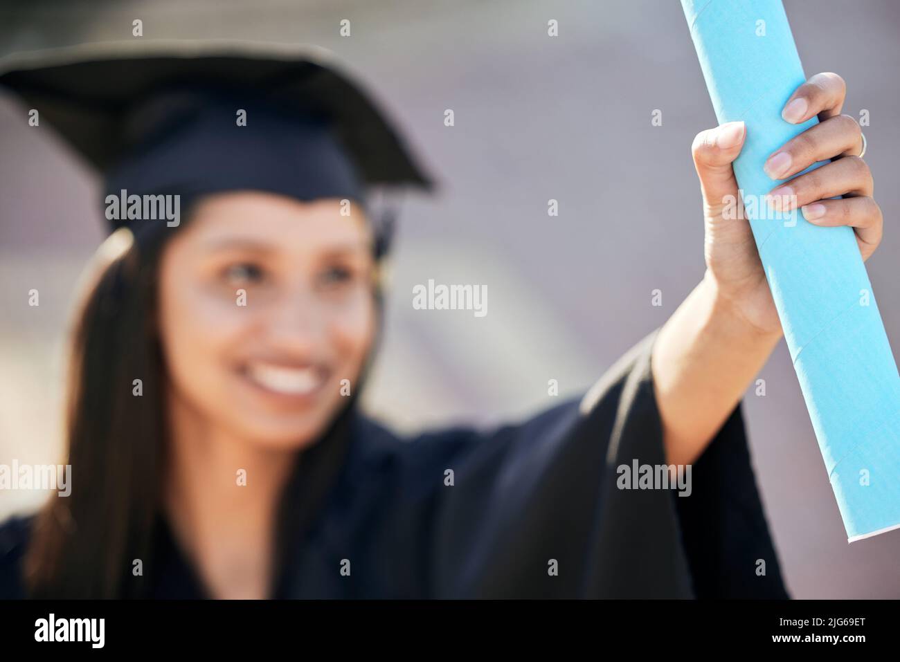 Its official. Shot of a young woman holding her diploma on graduation ...