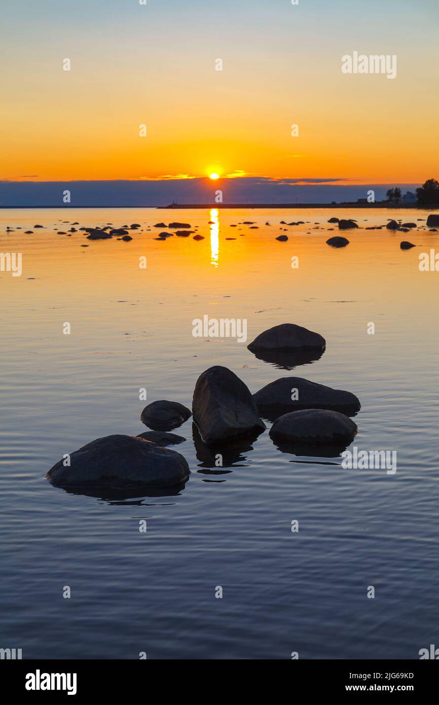 Rocky shore with stones sinking in the sea water. Sunset, long exposure ...