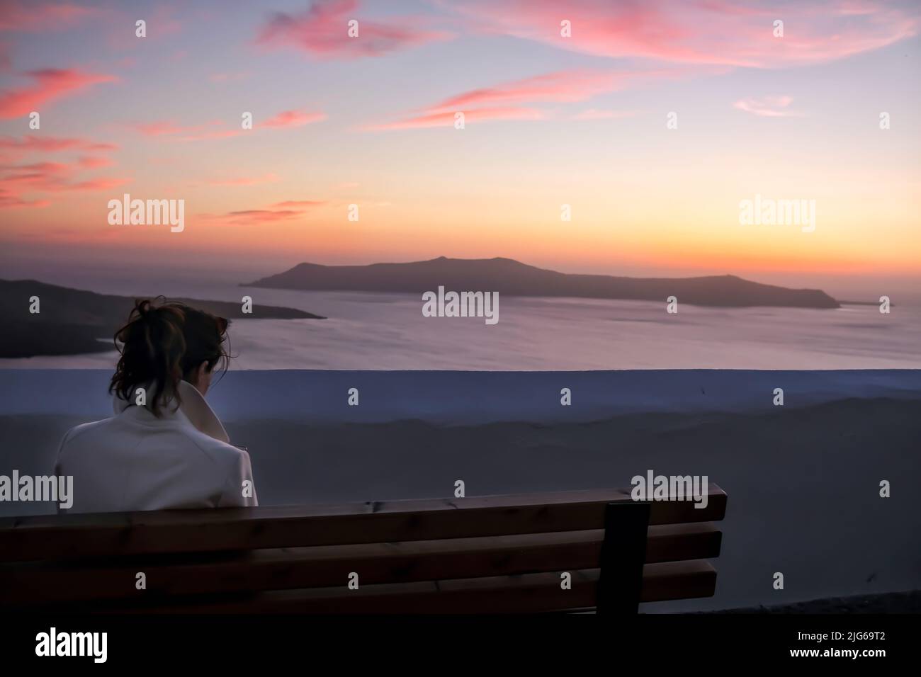 Santorini, Greece - May 14, 2021 : View of a woman sitting at a bench ...