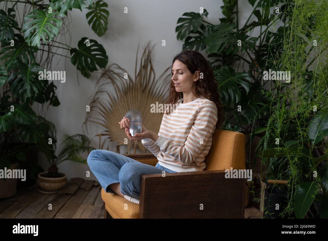 Calm smiling female playing with spring toy for stress relief has break ...