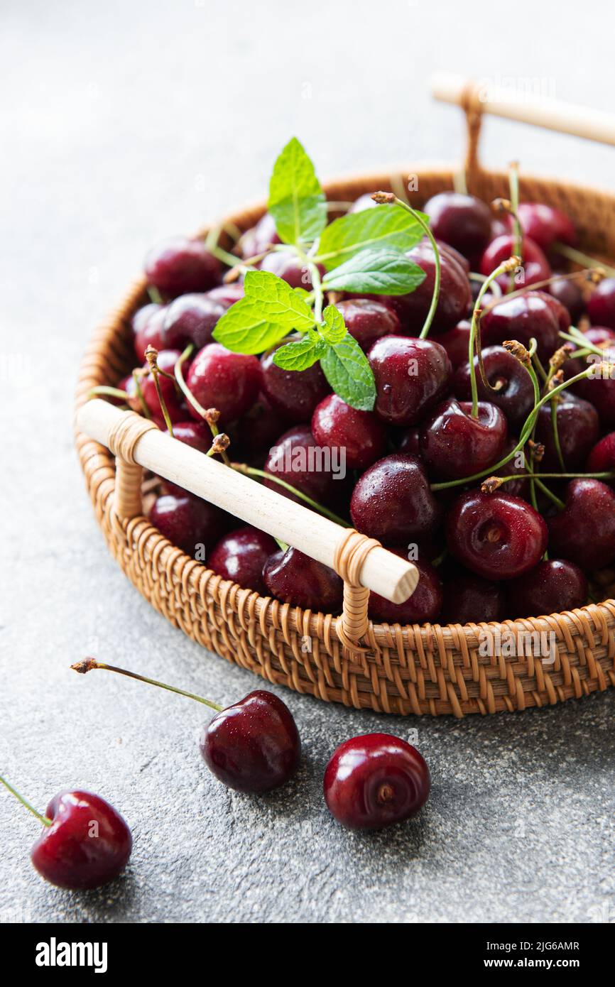 Fresh red cherries fruit on wicker tray on concrete background Stock ...