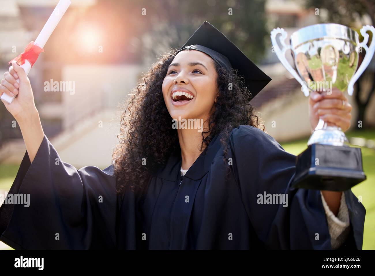 She came out tops. Shot of a young woman holding a trophy and cheering ...