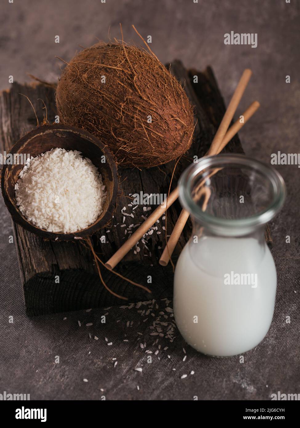 Bottle of coconut vegan milk with straws, whole coconut and flakes ...