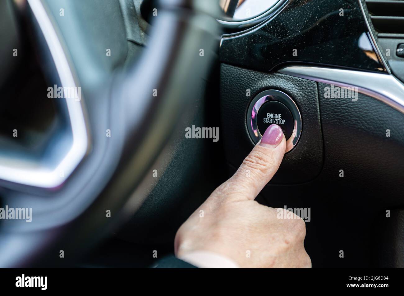 Woman starts the car engine with start-stop button. Modern car interior ...