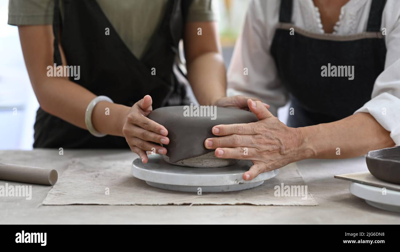 Young woman potter and mature woman making ceramic pot from clay in ...