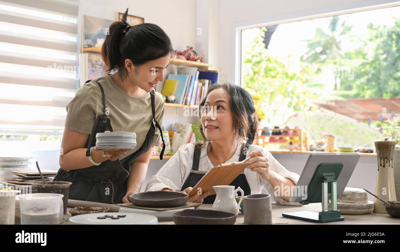 Handicraft pottery shop owners packing product in cardboard box for ...