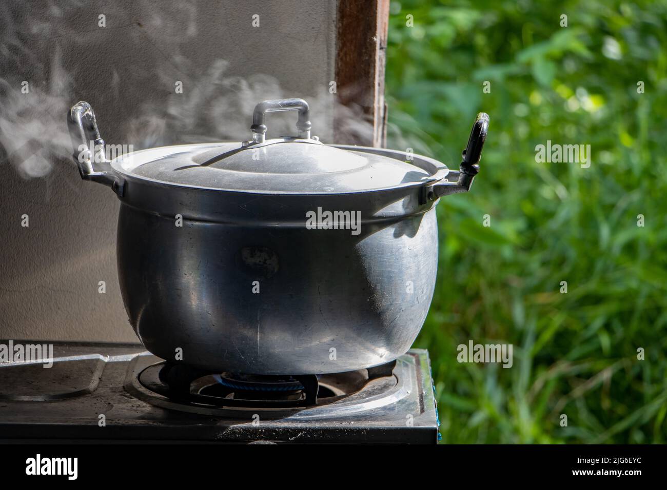 Preparing food by cooking in a pot on the stove next to an open door to ...