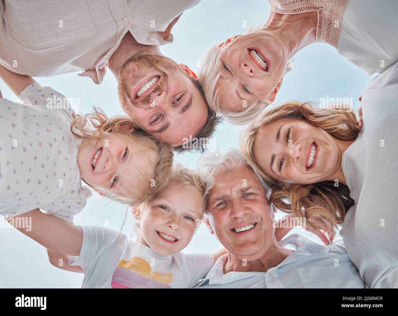 Below shot of multi-generation family smiling in a huddle against the ...