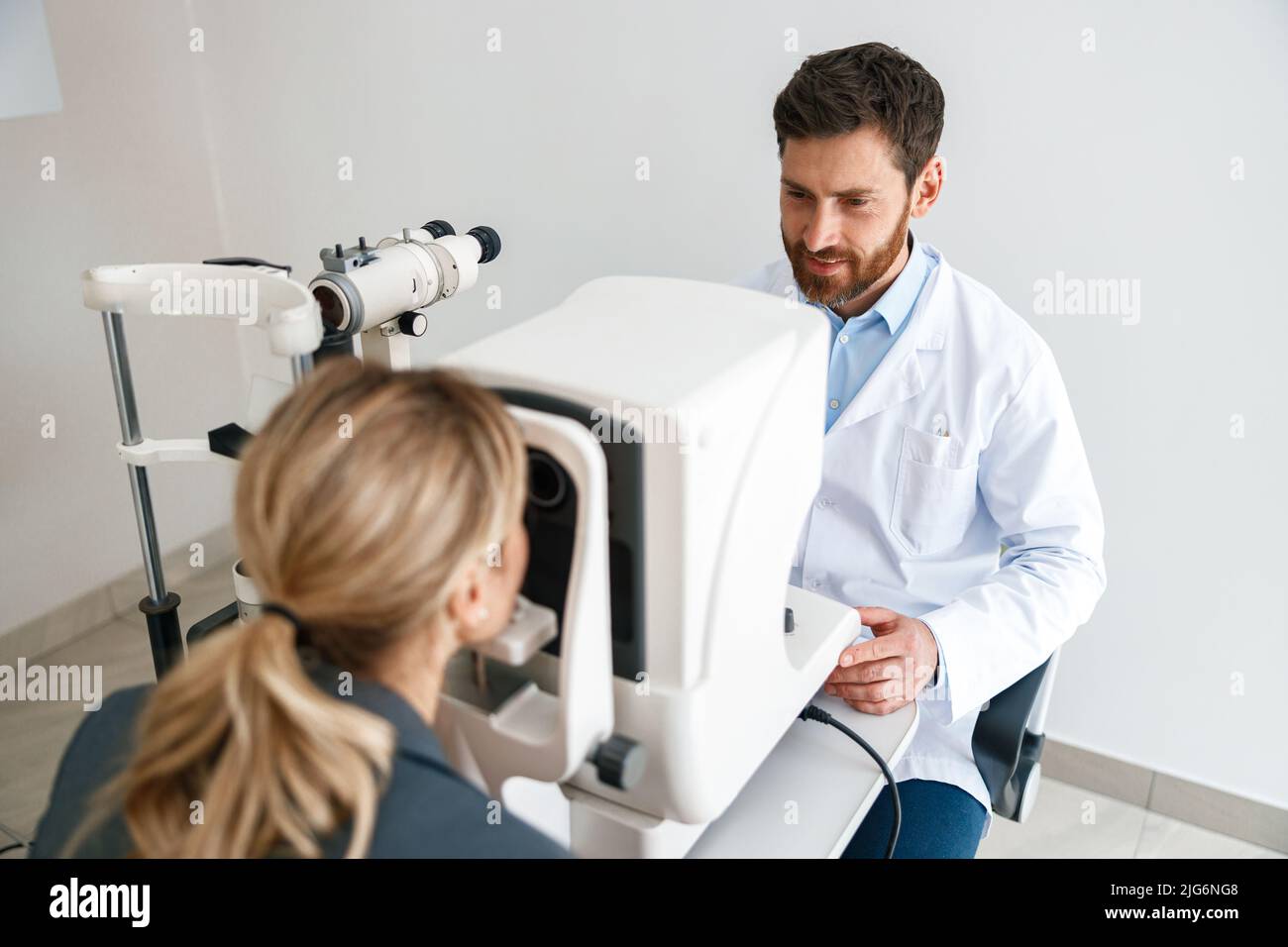 Male ophthalmologist checks a patient's vision at an opticians shop or ...
