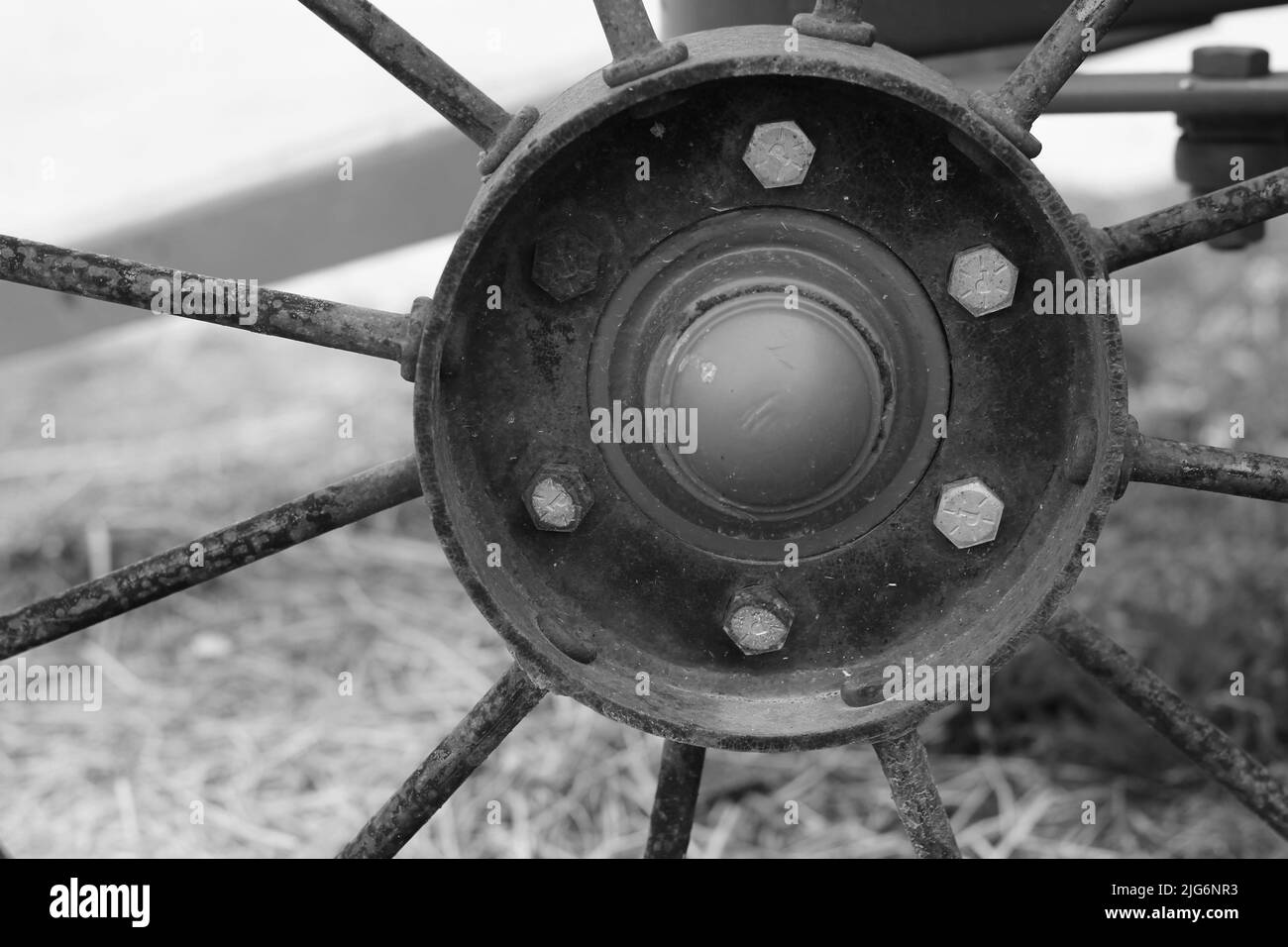 A vintage metal tractor wheel with an axle and exposed spokes in black ...