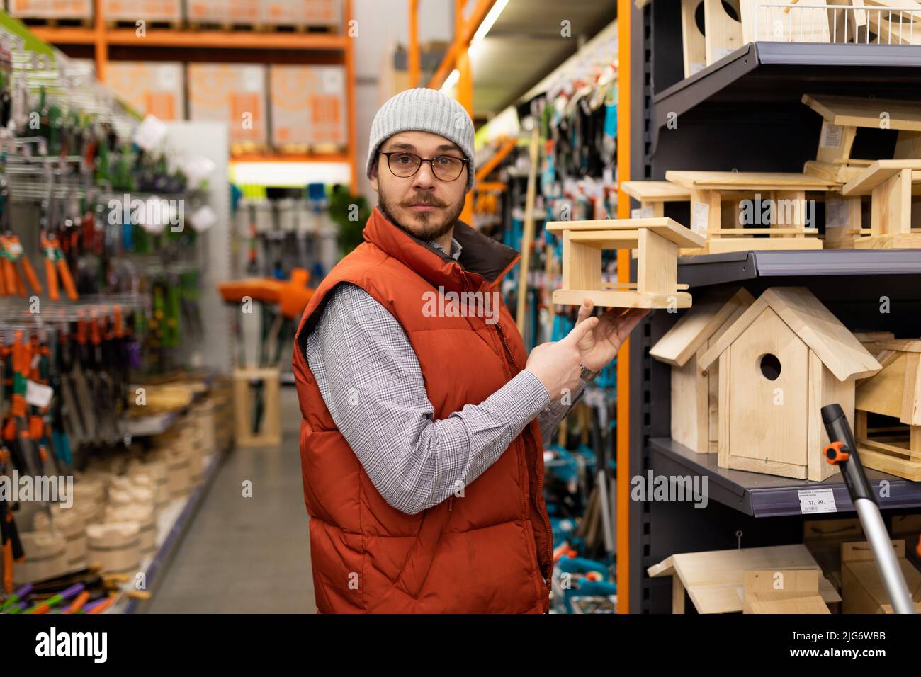 young male customer in a hardware store chooses a birdhouse for birds ...