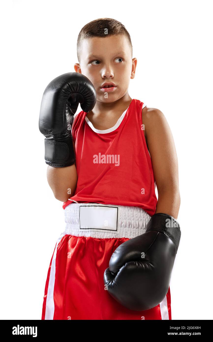 Portrait of kid, young boxer in boxing gloves and red unifprm posing ...