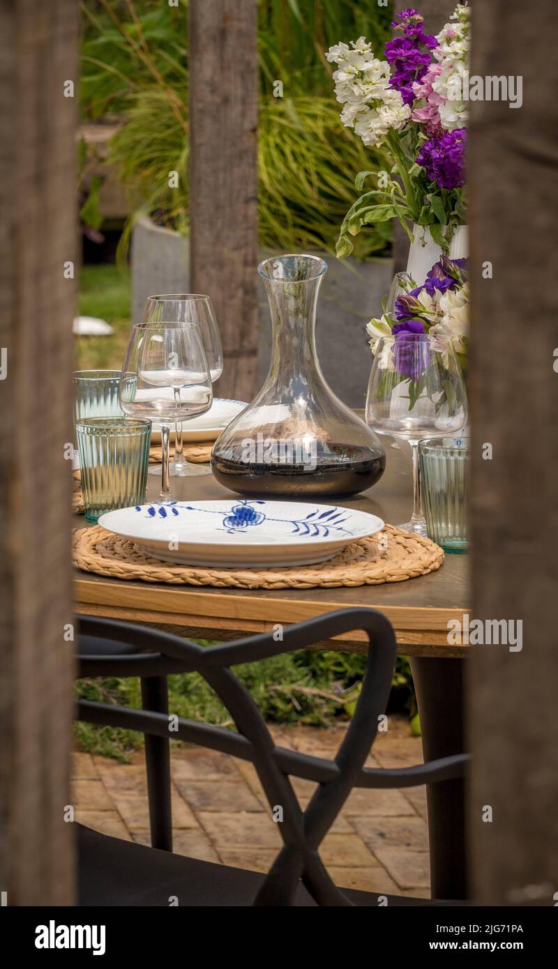 Garden table set for lunch, framed between vertical wooden posts in a ...