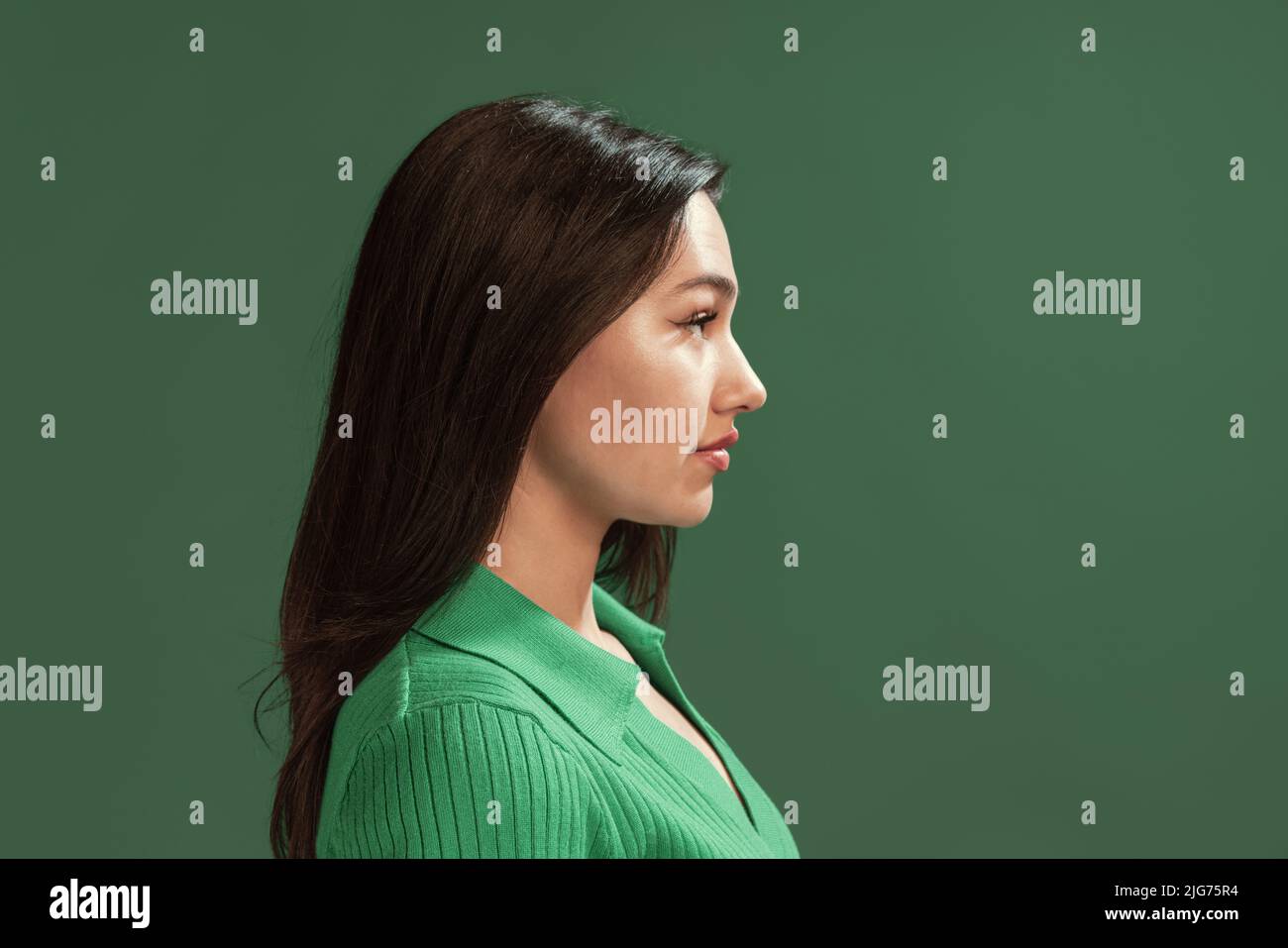 Portrait of beautiful young girl posing isolated over green studio ...