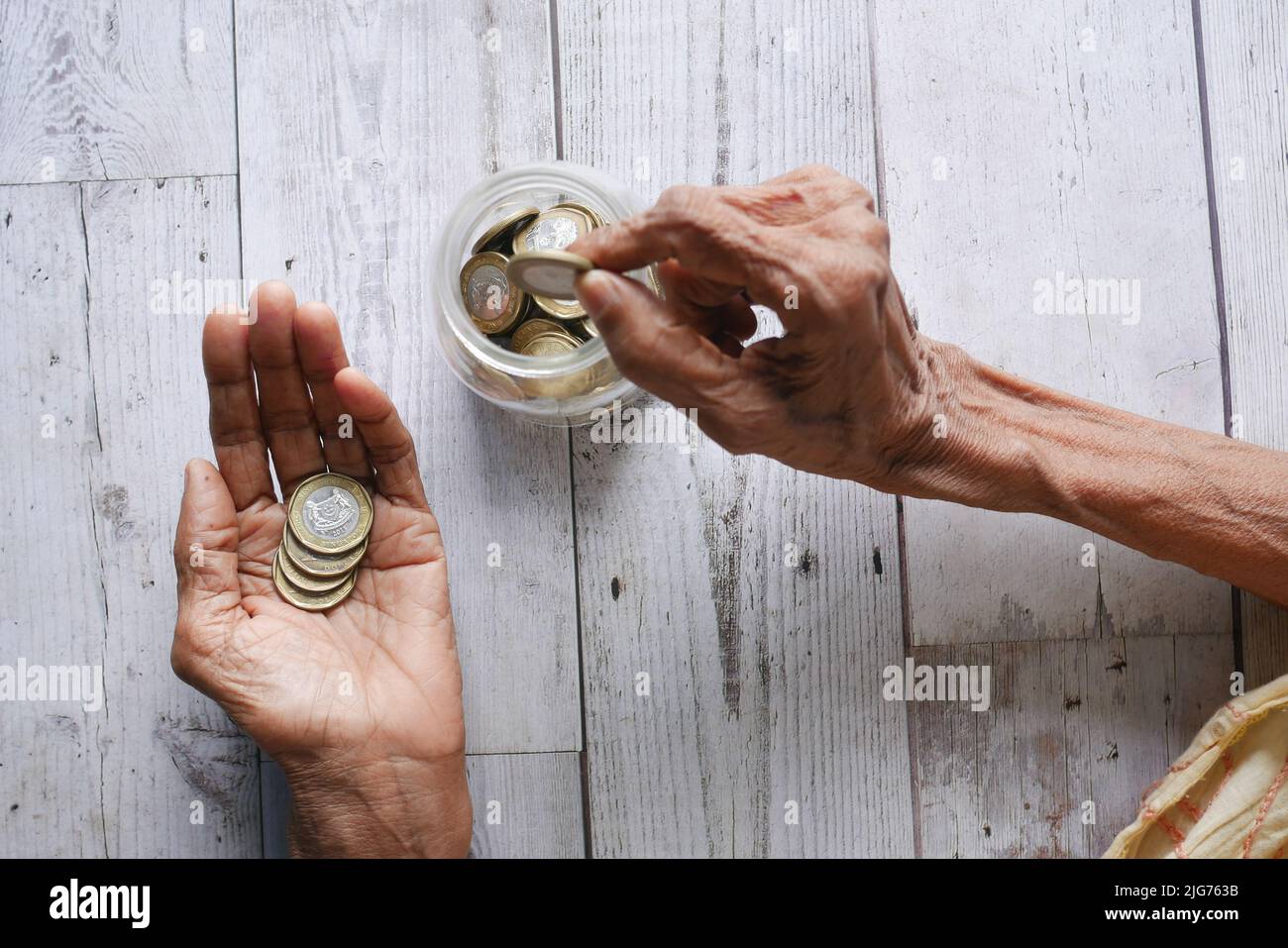 top view of senior women hand saving coins in a jar Stock Photo - Alamy