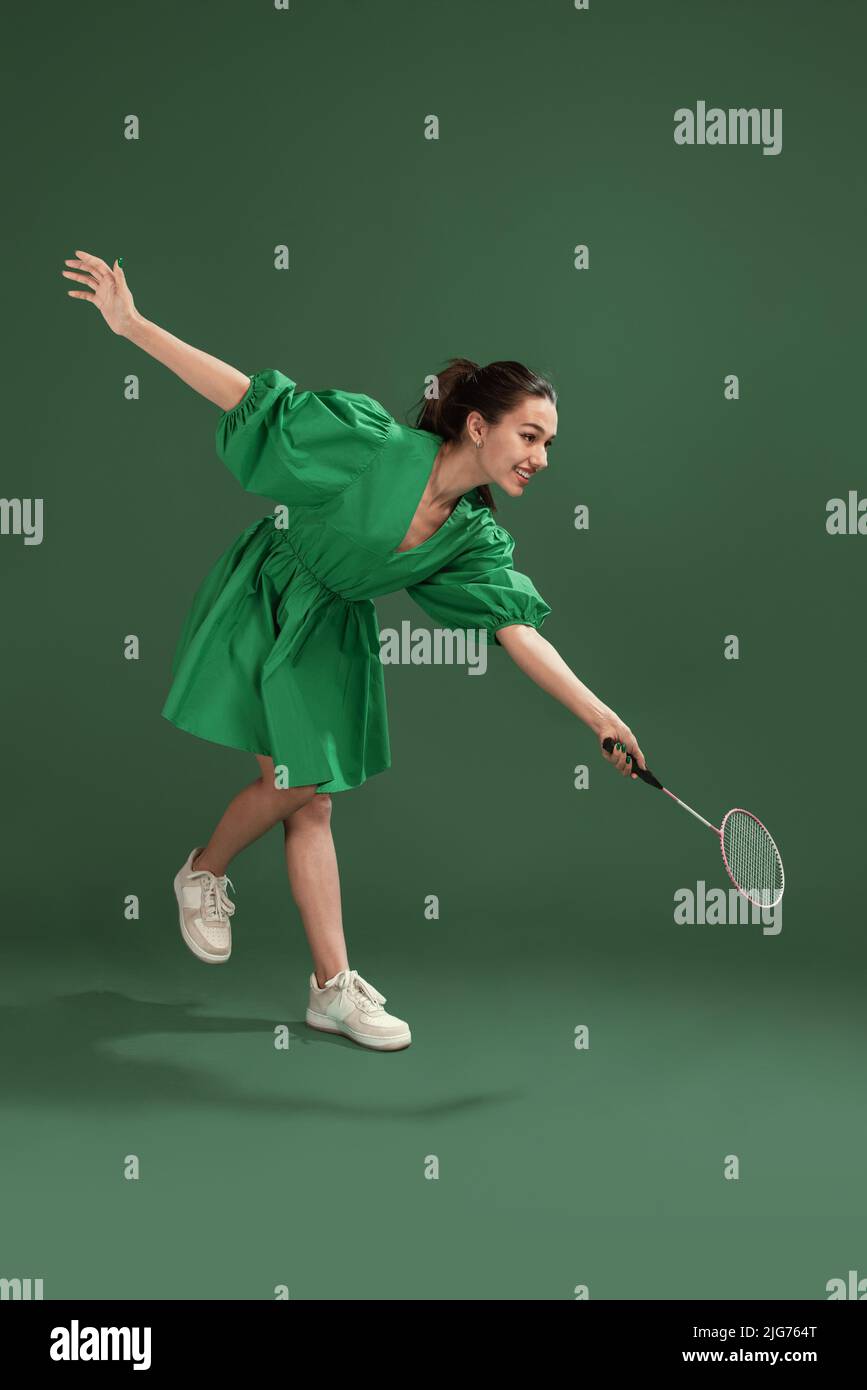 Portrait of cheerful young girl posing in dress, playing badminton ...