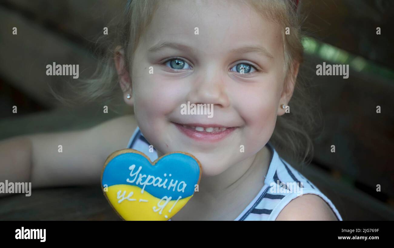 Little blonde girl holds gingerbread in Ukrainian national colors in ...