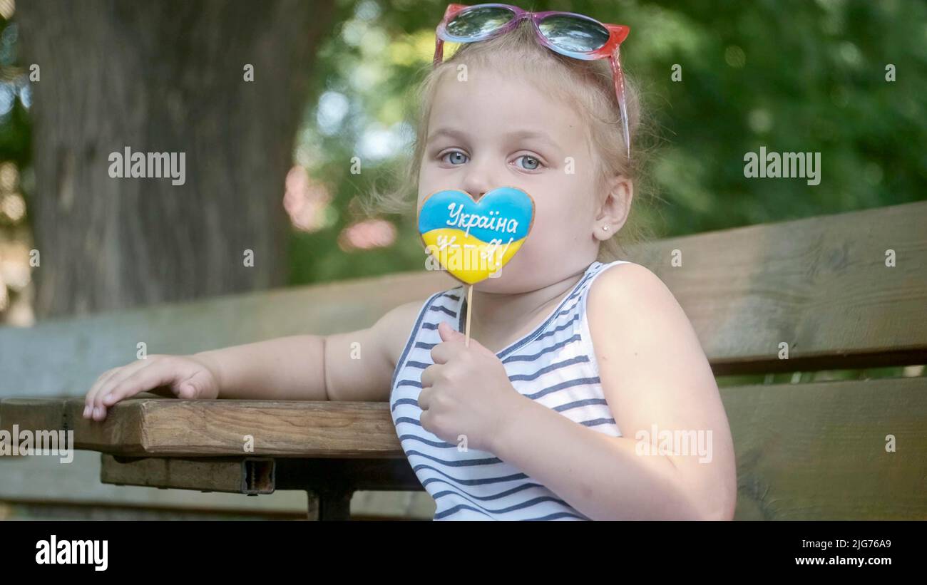Little blonde girl holds gingerbread in Ukrainian national colors in ...