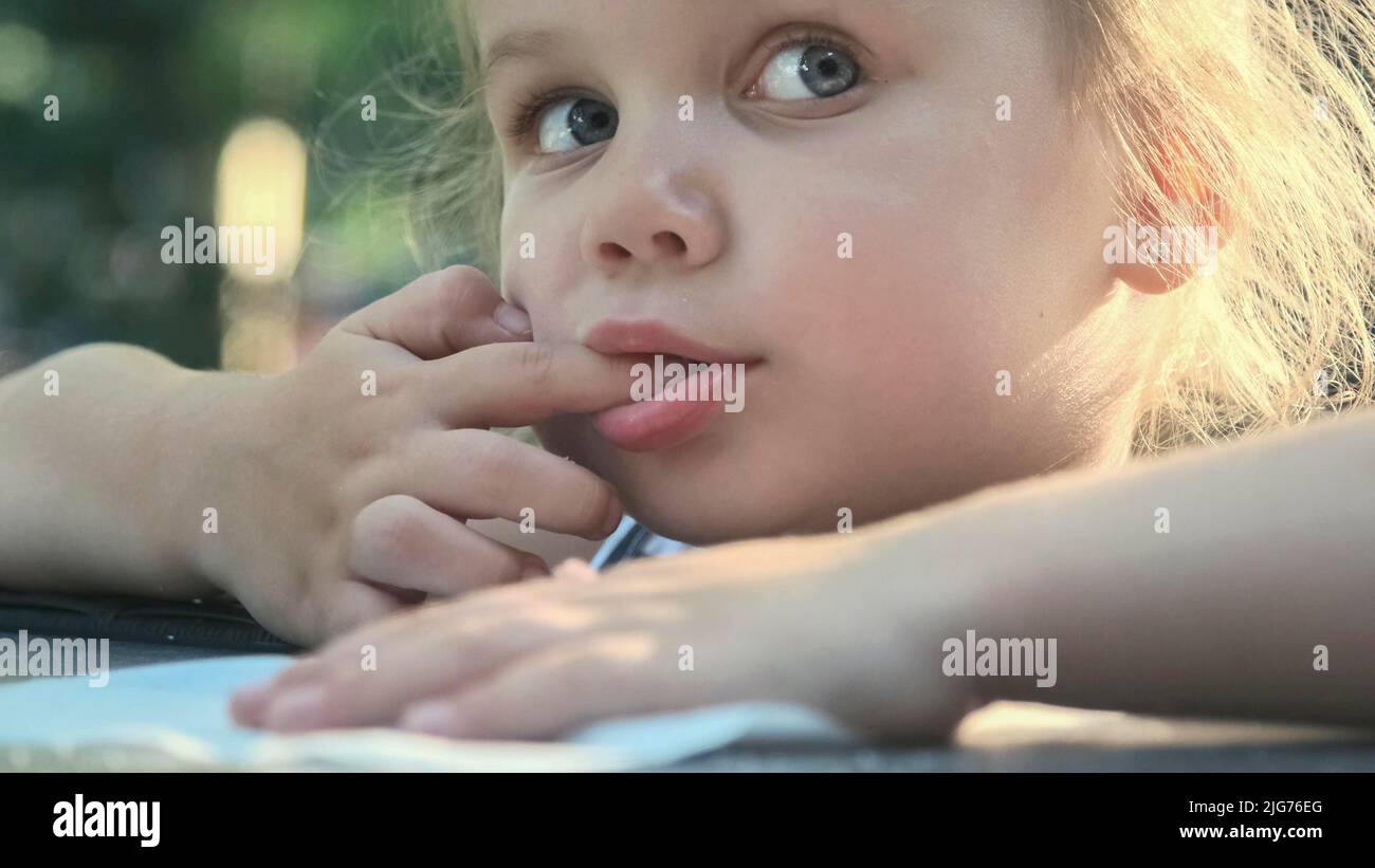 Little girl tastes salt. Close-up portrait of blonde girl takes salt ...