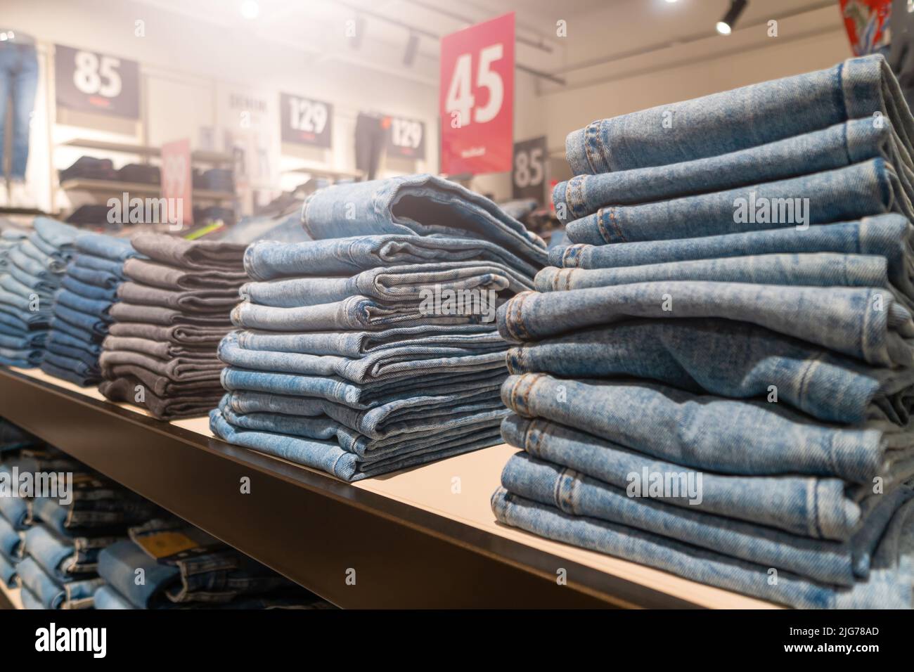 Stacks of jeans on a shelf in a mall store. Concept of buying, selling ...