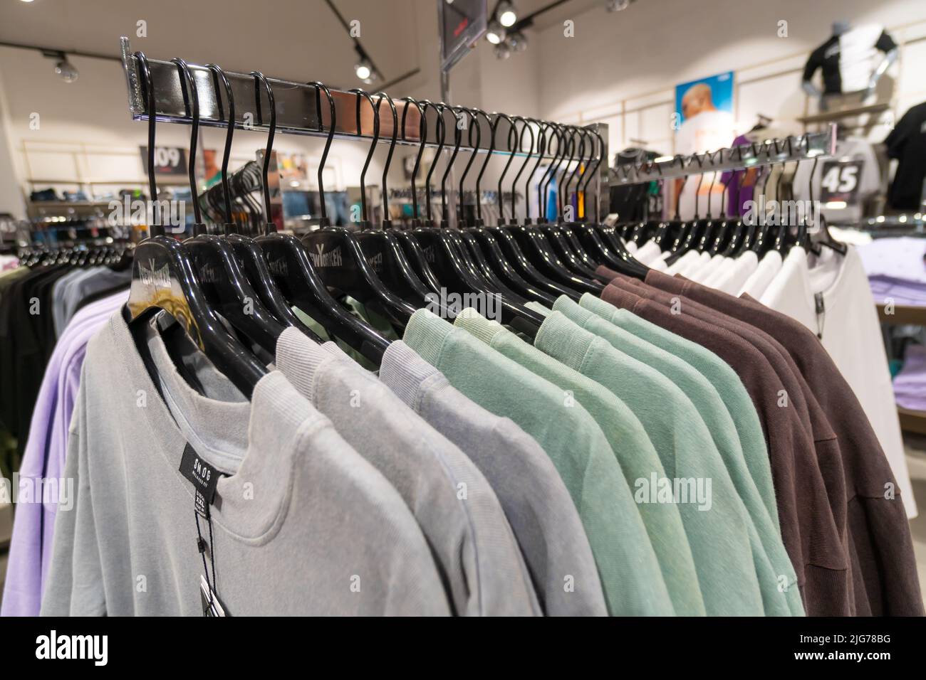 Sweatshirts on hangers in the mall store Stock Photo - Alamy