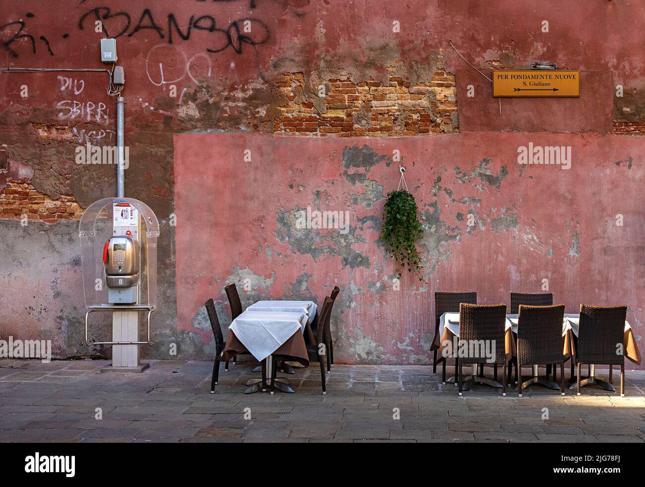 Public telephone booth and outdoor restaurant seating in front of pink ...