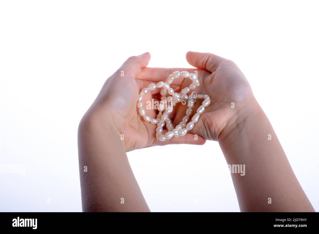 Hand holding a pearl necklace on a white background Stock Photo - Alamy