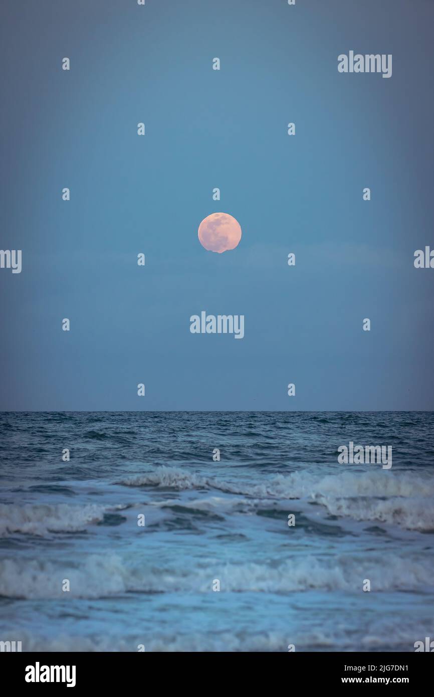 Detailed full moon over dark waves of the Atlantic Ocean on a clear ...