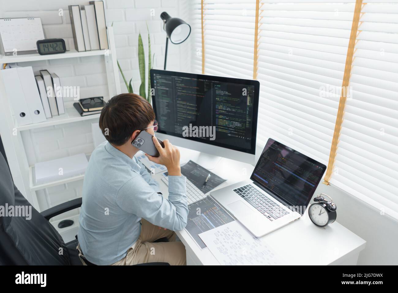 Software development concept, Male programmer talking on smartphone and check data code on ...