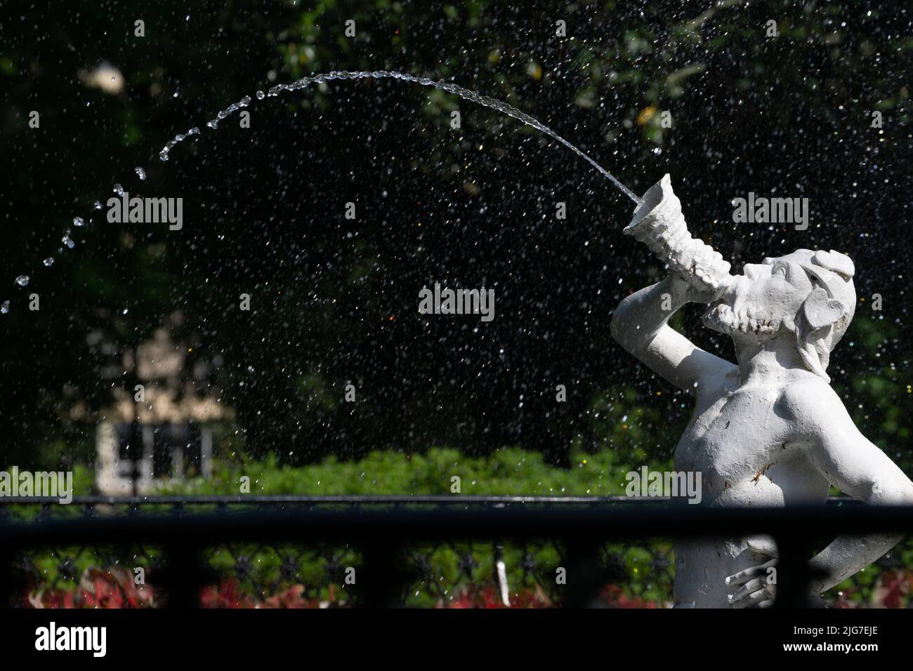 Water shoots out of a shell that is being blown by a Triton statue in ...