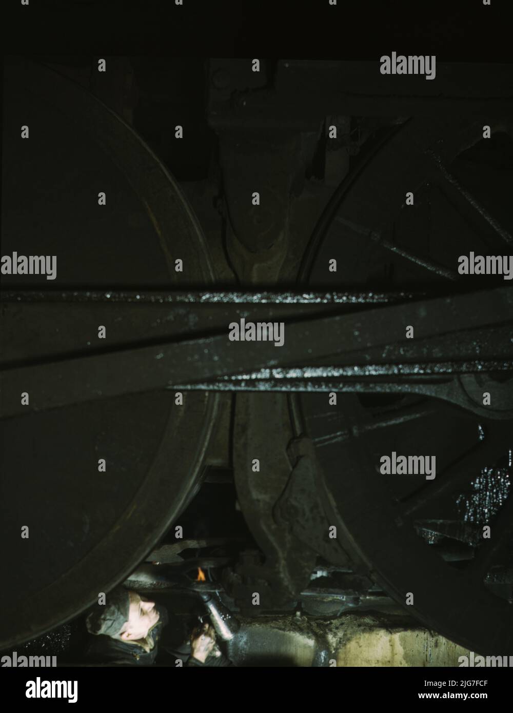 Worker inspecting a locomotive on a pit in the roundhouse at the C & NW ...