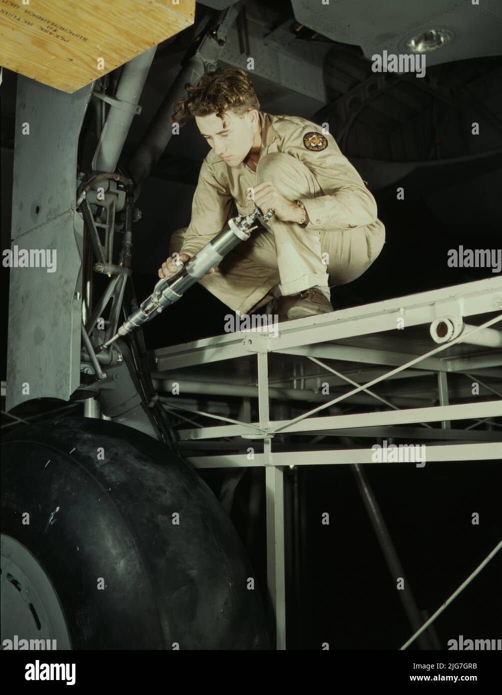 A hydraulic mechanic greasing the landing gear of a transport, before ...