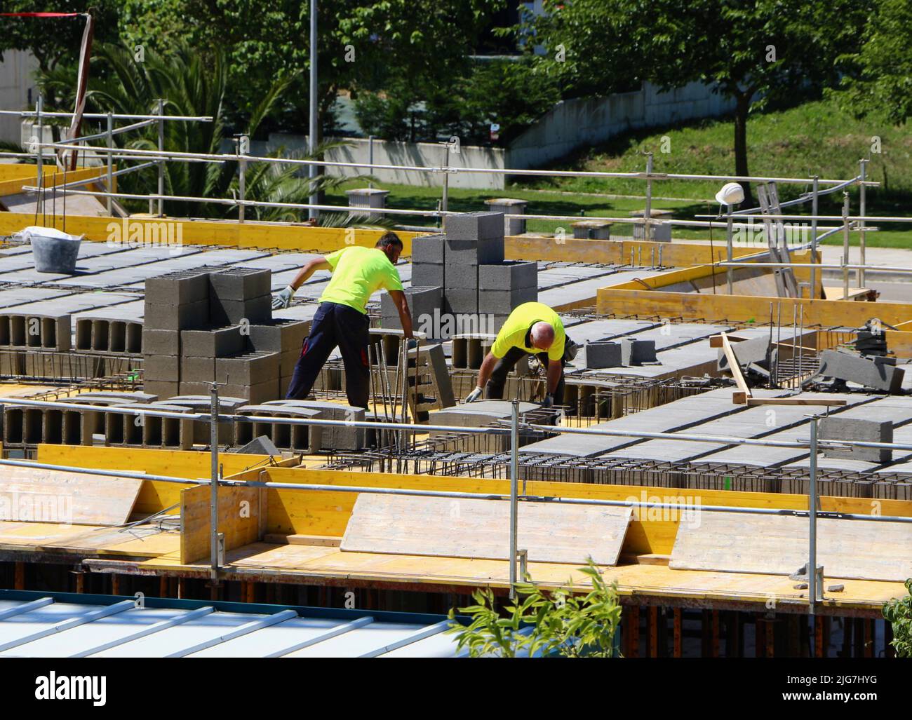 Two construction workers laying a floor on a construction site with 3 ...