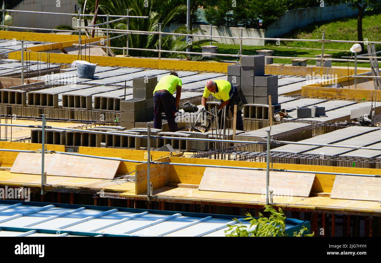 Two construction workers laying a floor on a construction site with 3 ...