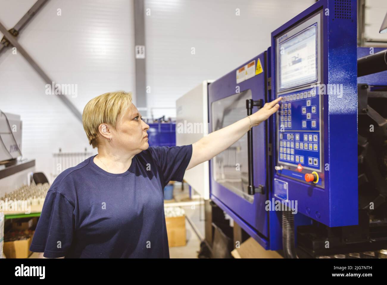 A worker woman presses a button and starts an automatic manufacturing ...
